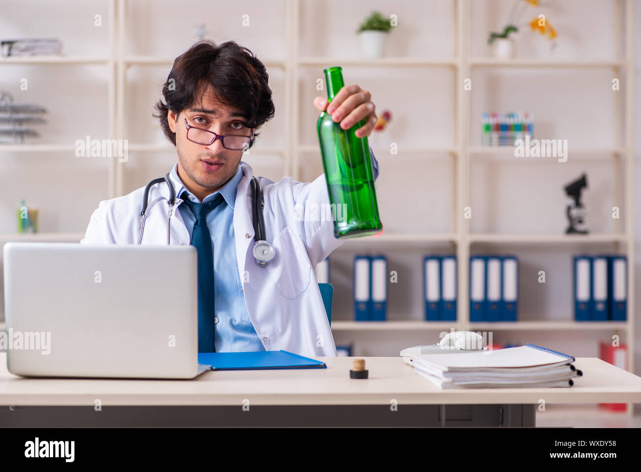 Young male doctor drinking in the office Stock Photo - Alamy