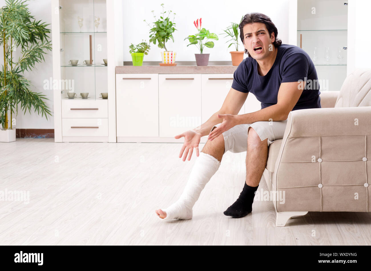 Leg injured young man suffering at home Stock Photo - Alamy
