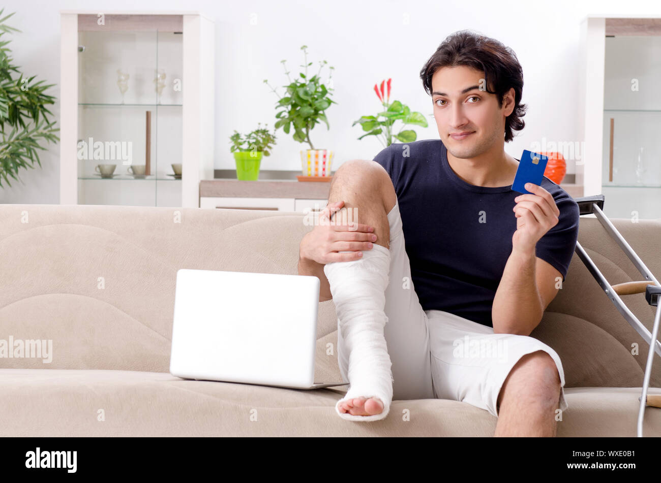 Leg injured young man suffering at home Stock Photo - Alamy