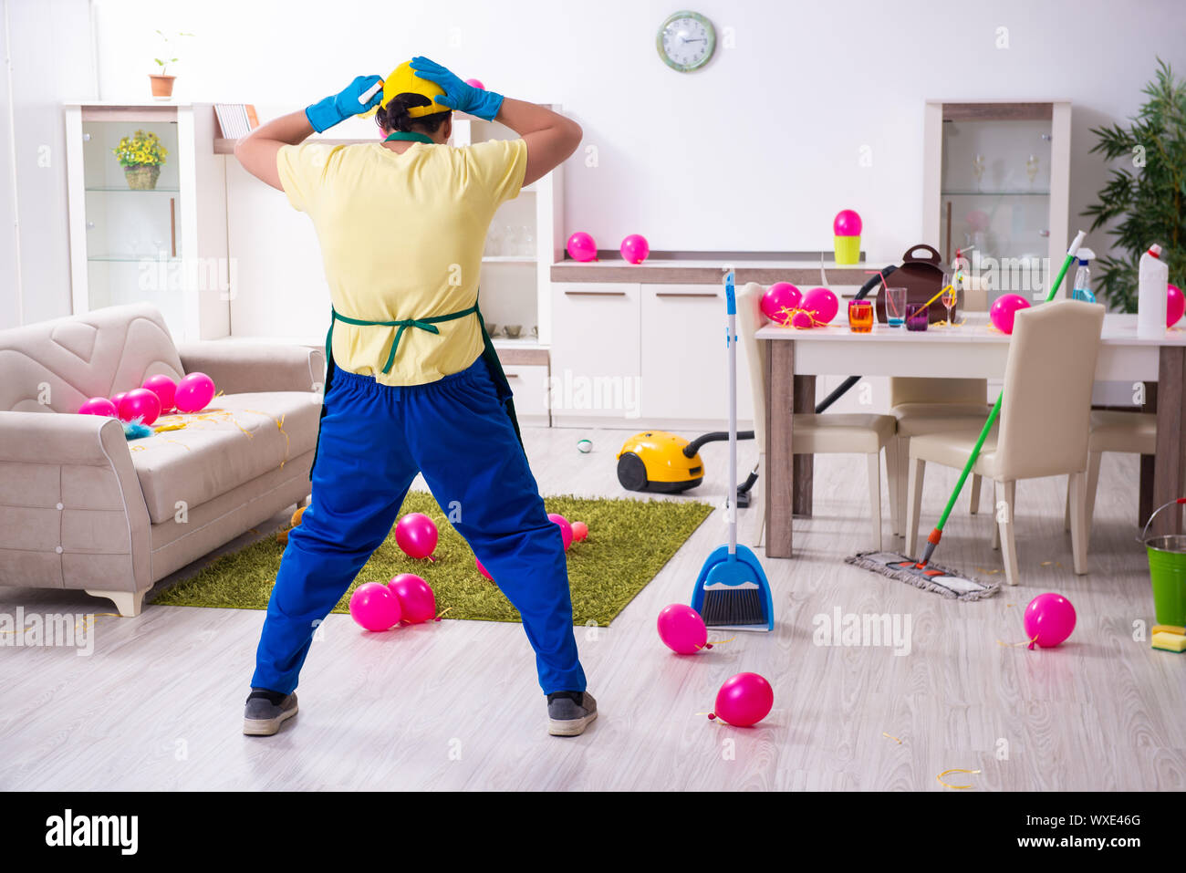 Young male contractor doing housework after party Stock Photo - Alamy