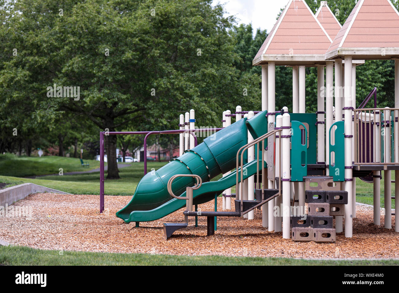 Empty playground with green slide, zip line, monkey bars and chain ...