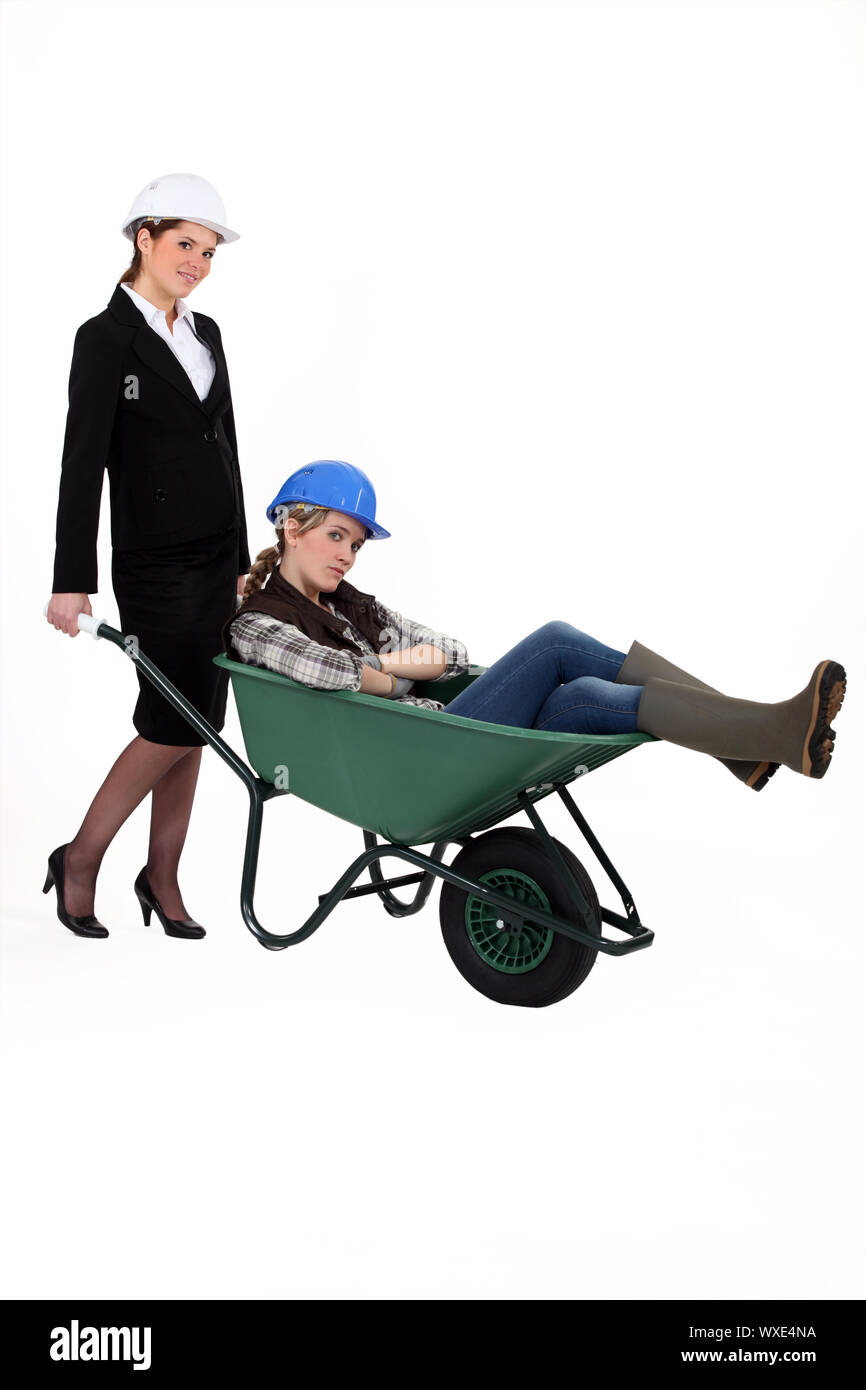 Female architect pushing colleague in wheelbarrow Stock Photo - Alamy