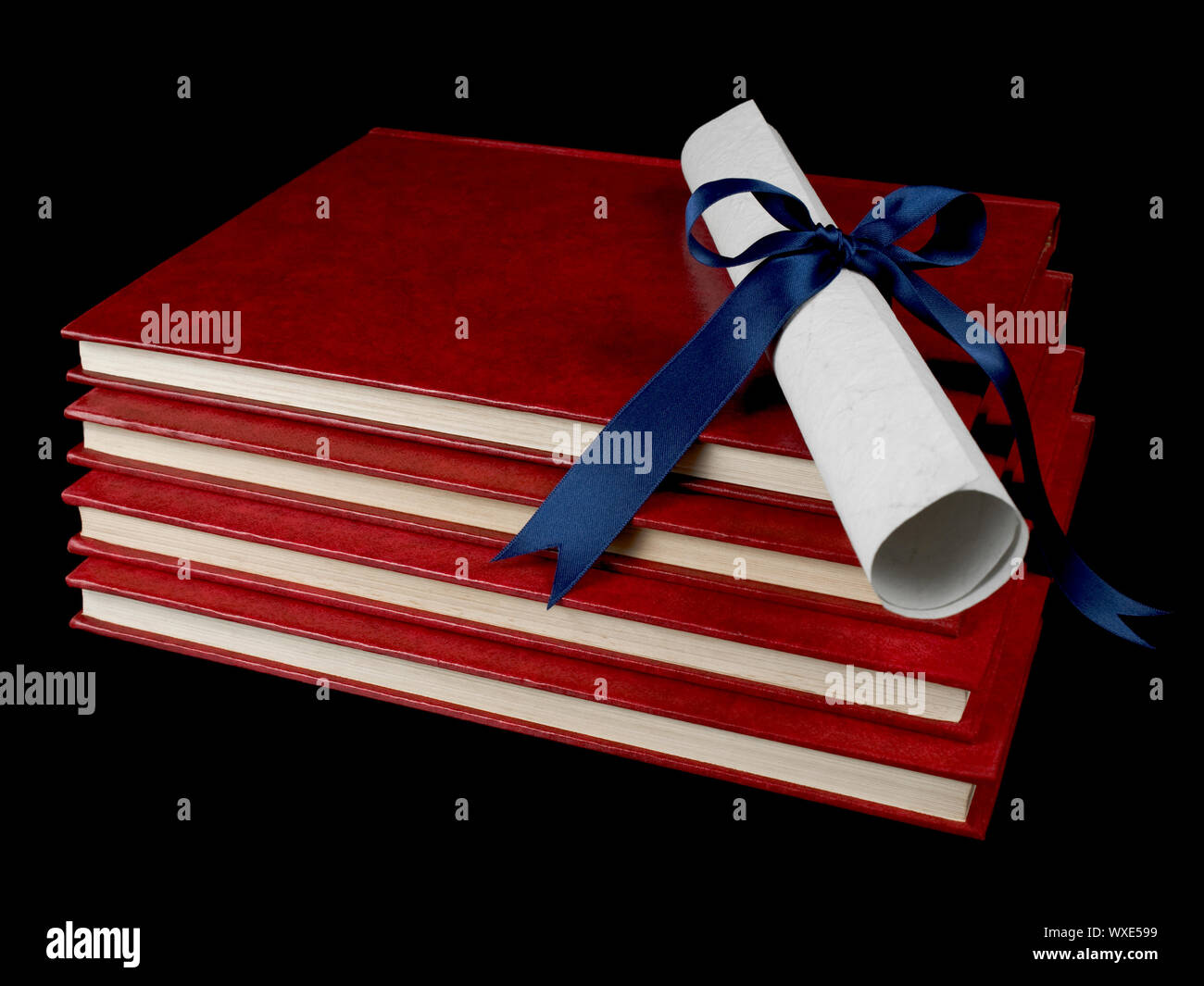 A diploma with blue ribbon over several books. Isolated on black Stock ...