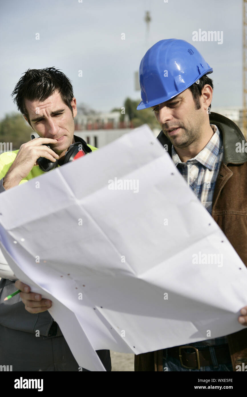 Foreman and colleague checking over plans Stock Photo - Alamy