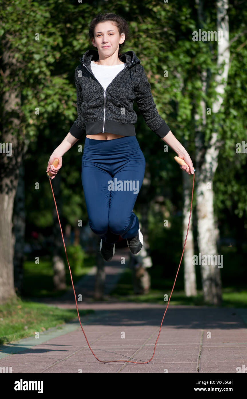 Beautiful young woman doing exercise with skipping rope at park ...