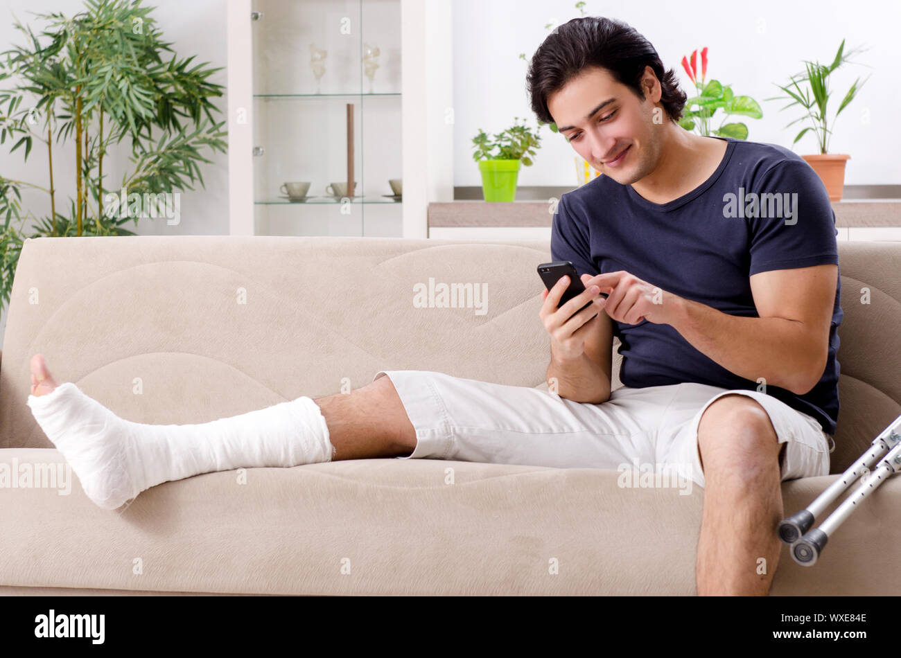 Leg injured young man suffering at home Stock Photo - Alamy