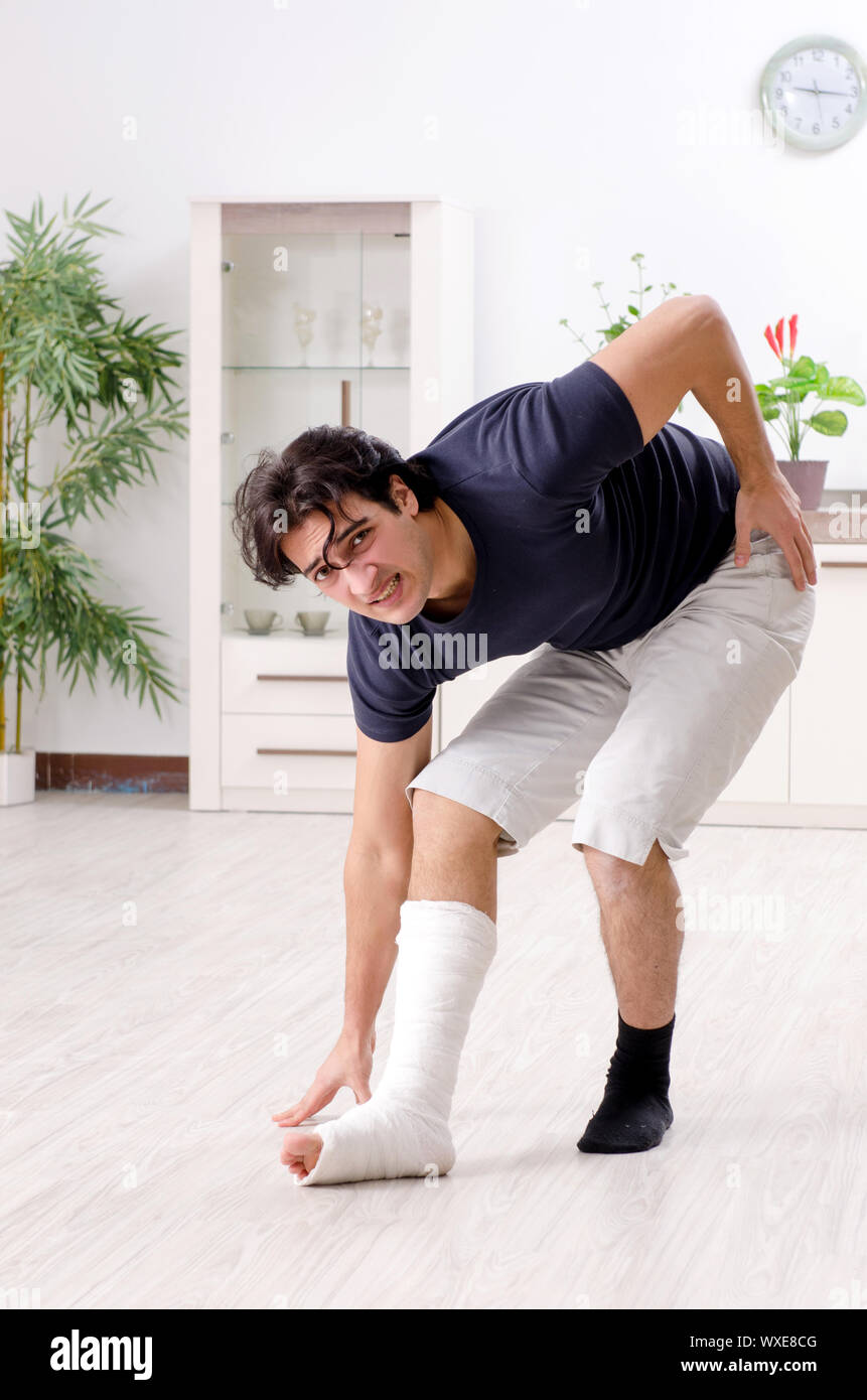 Leg injured young man suffering at home Stock Photo - Alamy