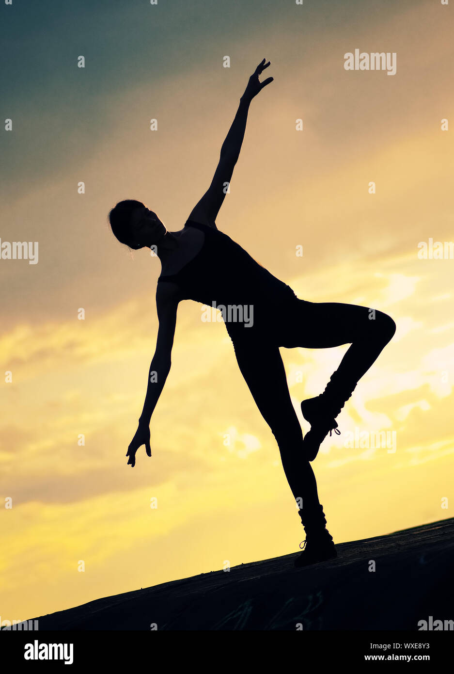 Silhouette photo of dancing woman in modern pilates style over sunset ...