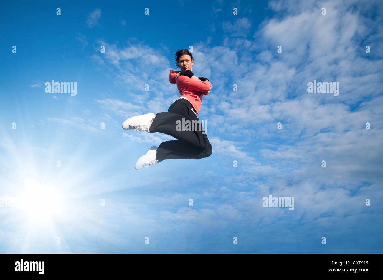 Beautiful sport woman in urban sportswear jumping and fly over blue sky ...