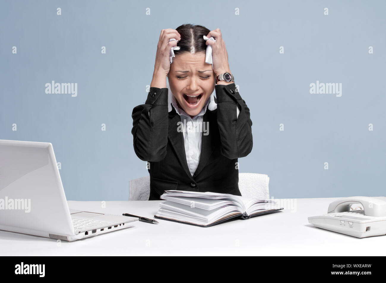 Sad business woman in office working with white table, laptop and diary ...
