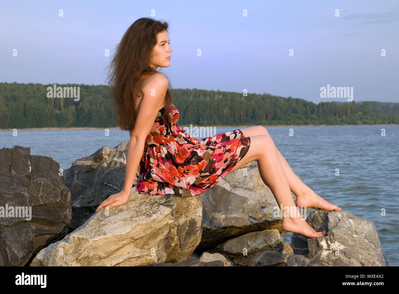 Beautiful girl sit on rock on sea coast Stock Photo - Alamy