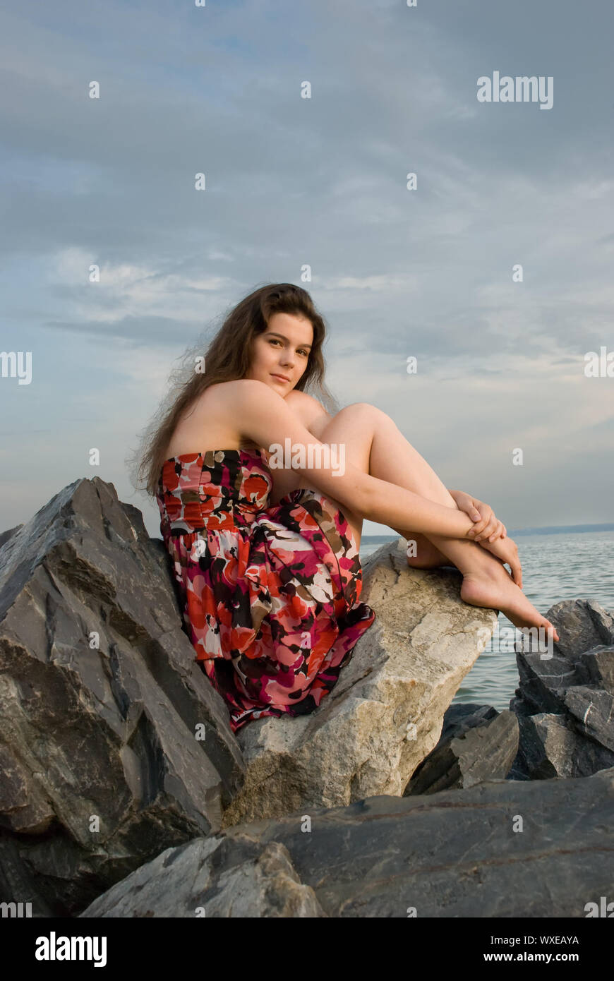 Beautiful girl sit on rock on sea coast Stock Photo - Alamy