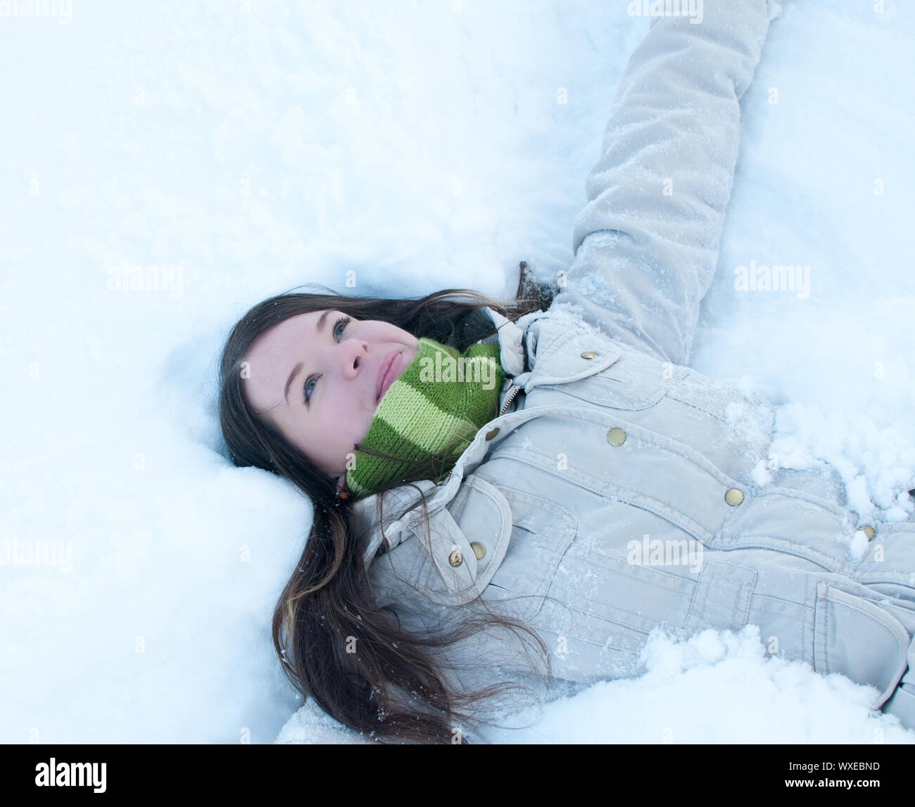 Winter lifestyle. Beautiful girl lying in snow. Snow angel Stock Photo ...