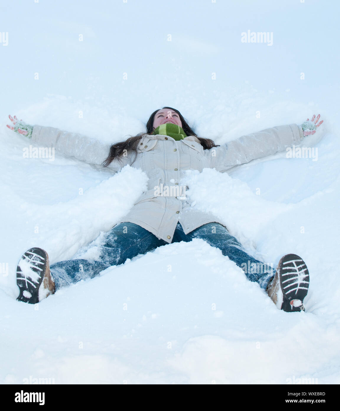 Winter lifestyle. Beautiful girl lying in snow. Snow angel Stock Photo ...