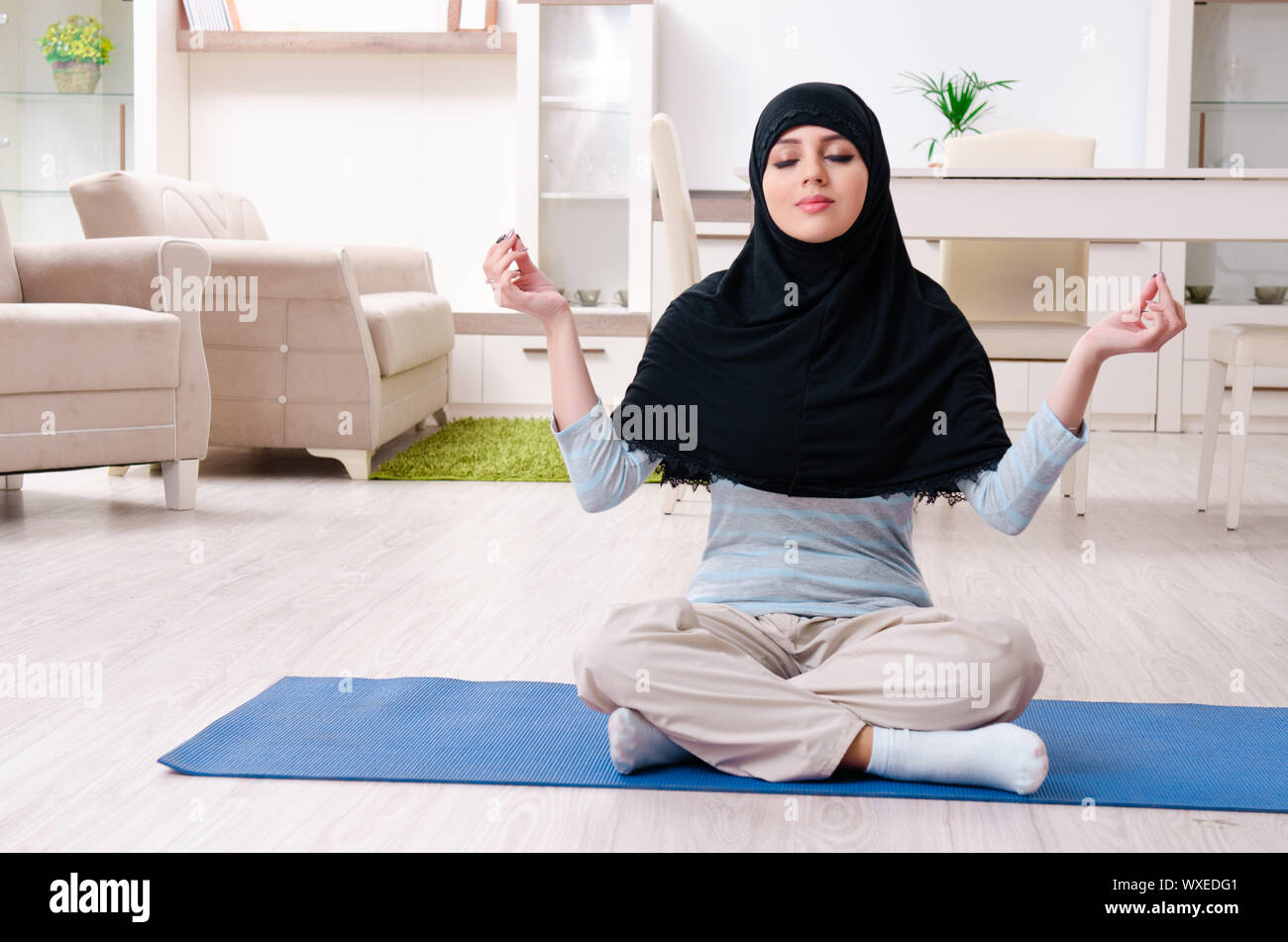 Young woman in hijab doing exercises at home Stock Photo - Alamy