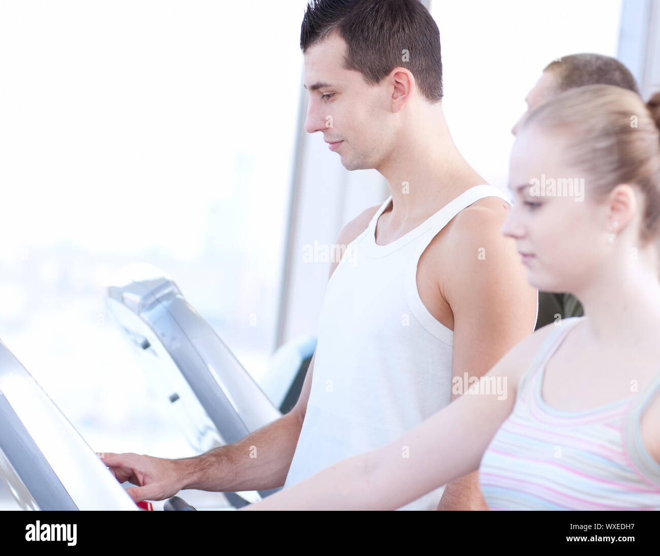 Young woman and man at the gym exercising. Run on a machine Stock Photo ...