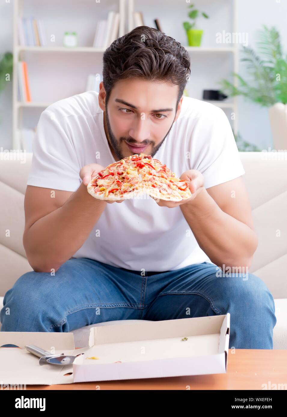 Man eating pizza having a takeaway at home relaxing resting Stock Photo ...