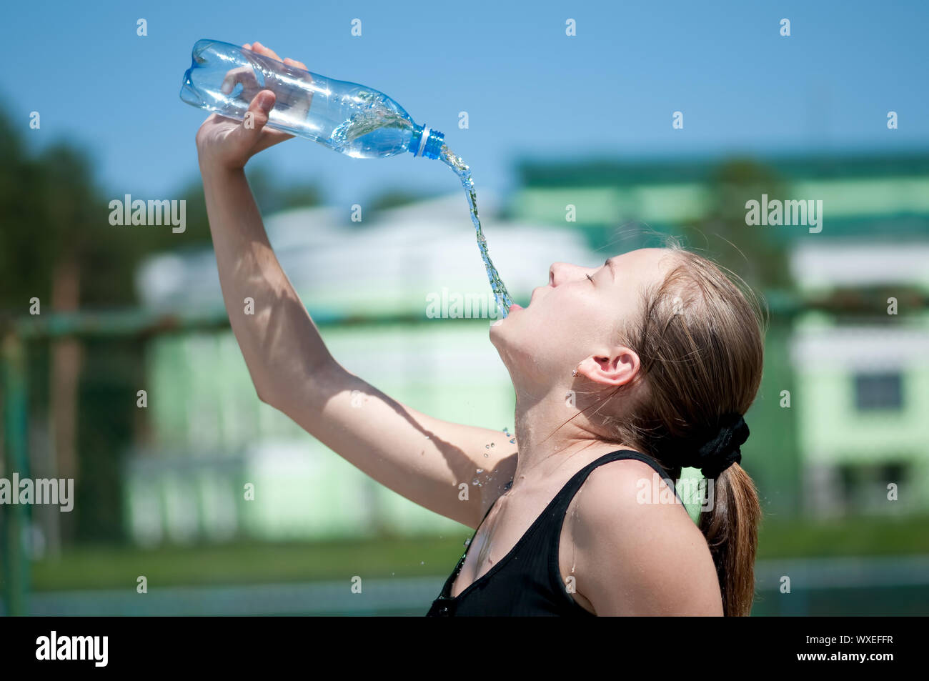 Beautiful young woman drinking water after exercise on sunny summer day ...