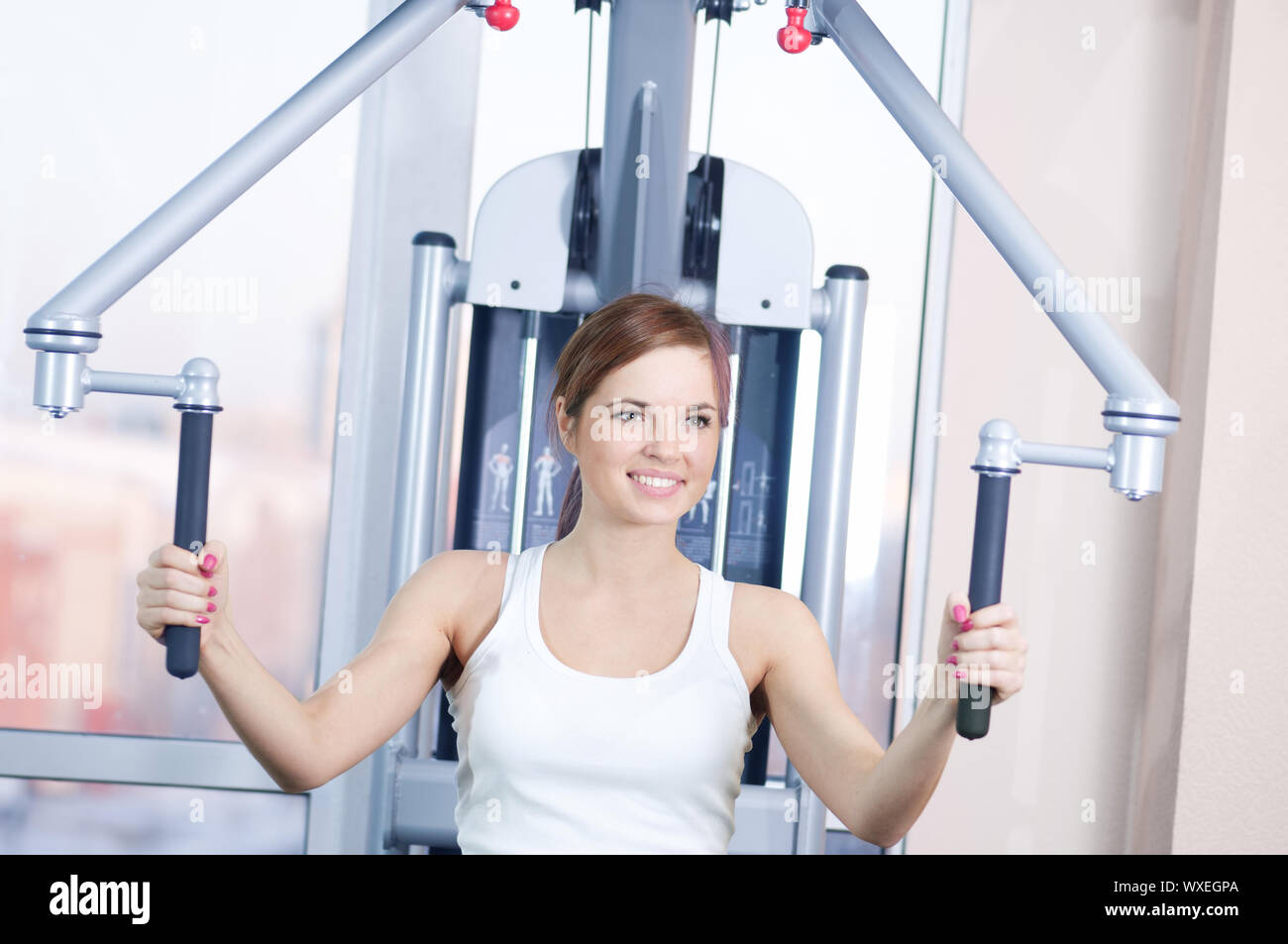 Young woman at the gym exercising on a machine Stock Photo - Alamy