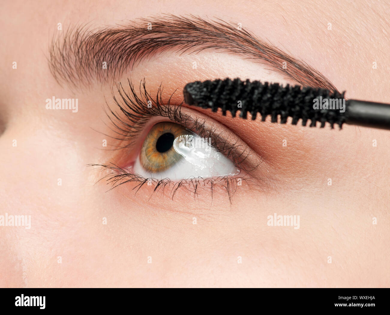 Beautiful young adult woman applying cosmetic mascara brush - close-up ...