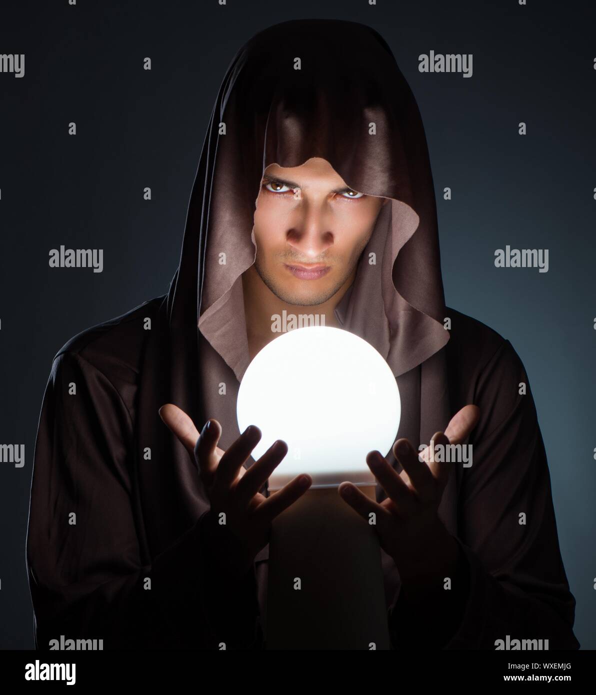 Young wizard with crystal ball in dark room Stock Photo - Alamy