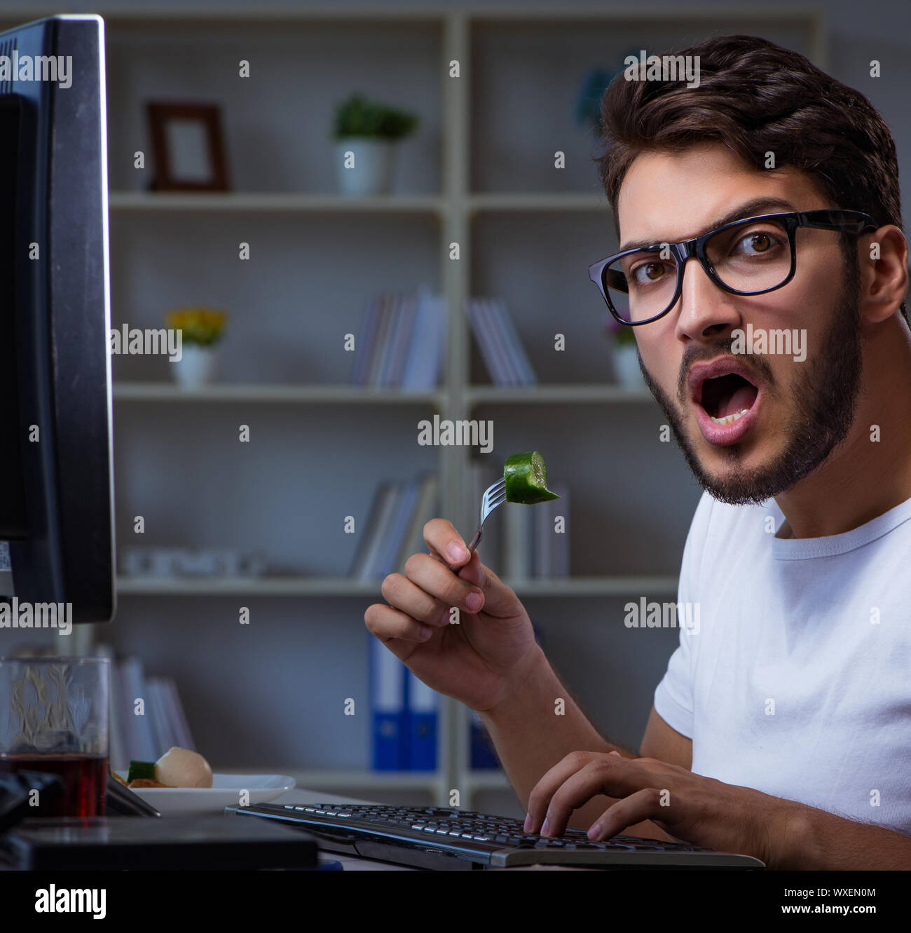 Young man staying late in office to do overtime work Stock Photo - Alamy