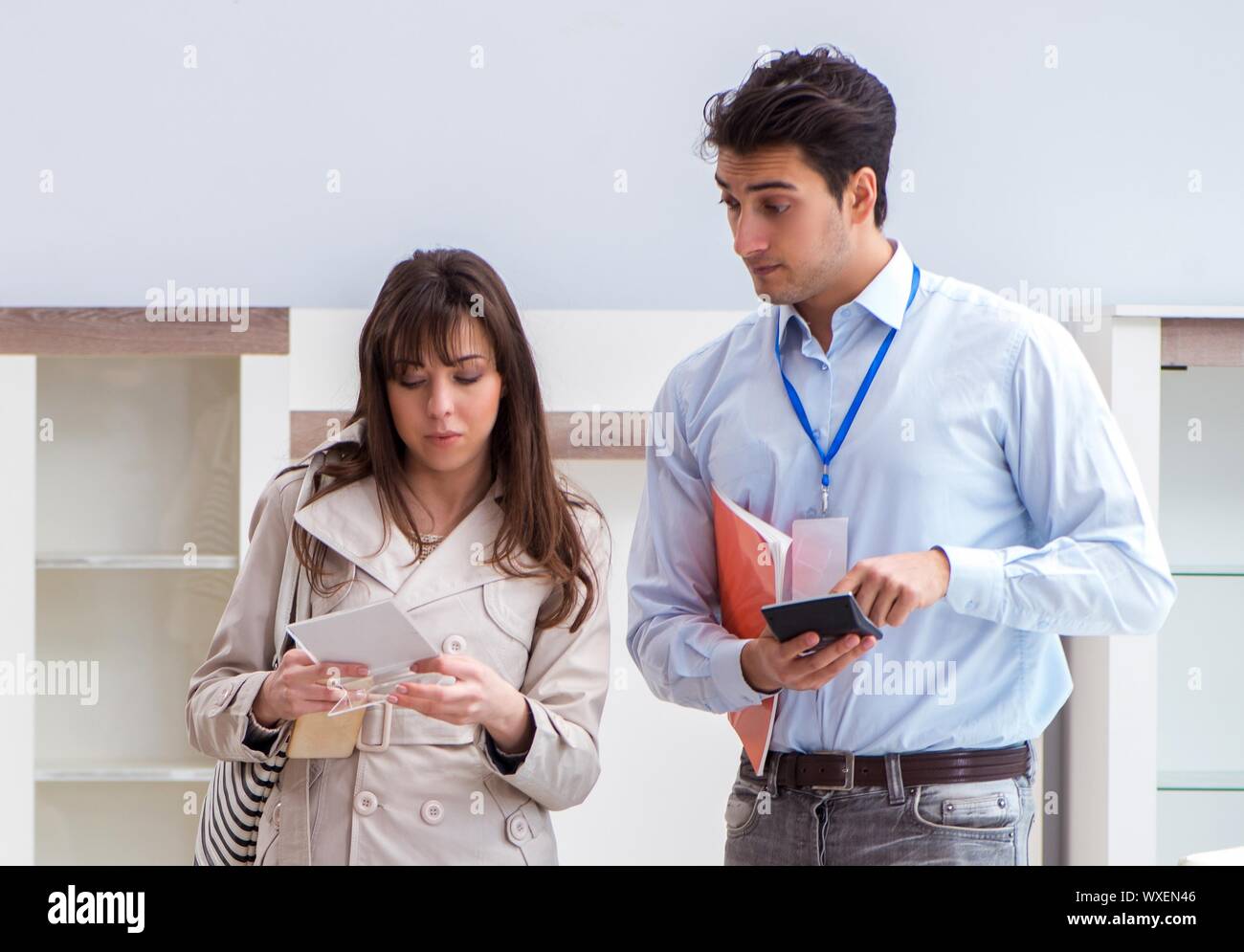 Salesman explaining to woman customer at furniture store Stock Photo ...