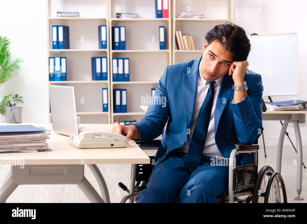 Male employee in wheelchair working at the office Stock Photo - Alamy