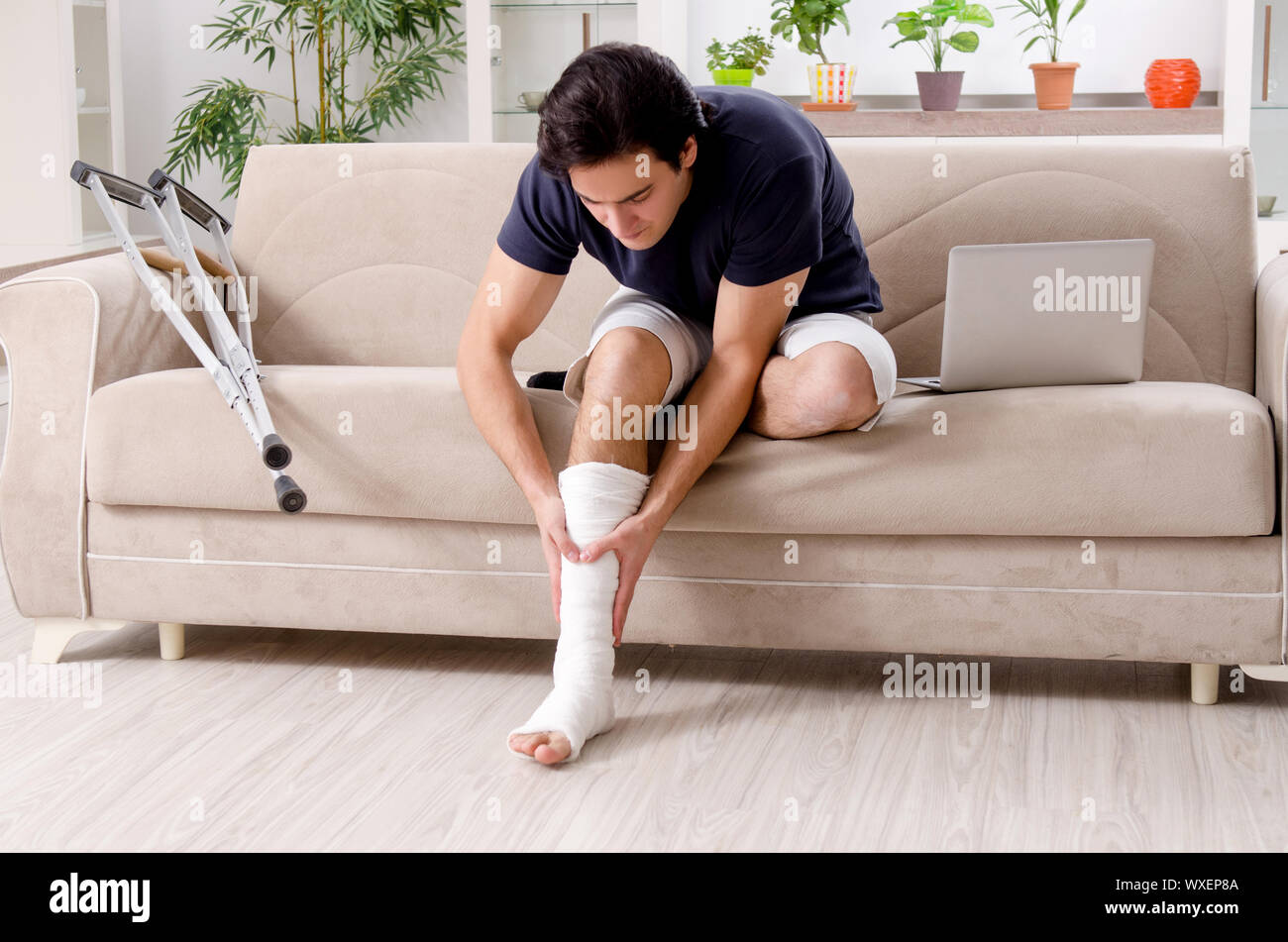 Leg injured young man suffering at home Stock Photo - Alamy