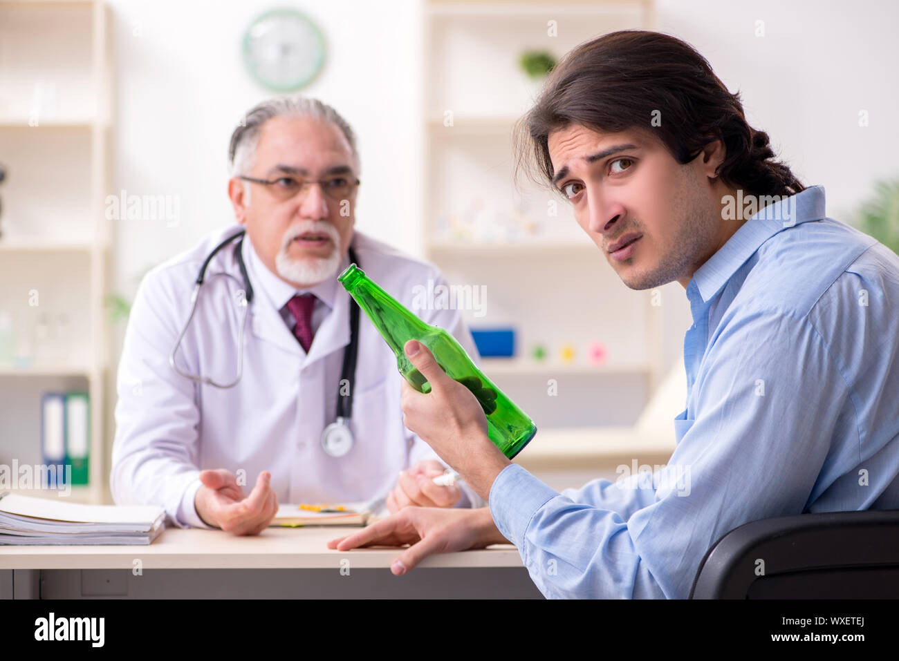 Young male alcoholic visiting old doctor Stock Photo - Alamy