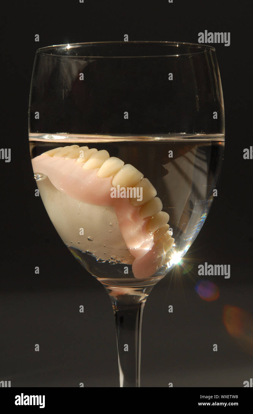 Dentures in a glass of water on black background Stock Photo - Alamy