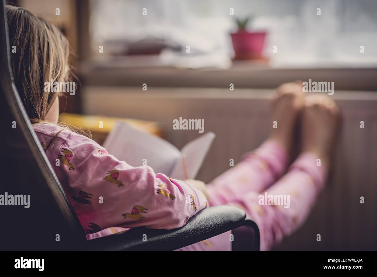 Girl in pyjama reading a book Stock Photo - Alamy