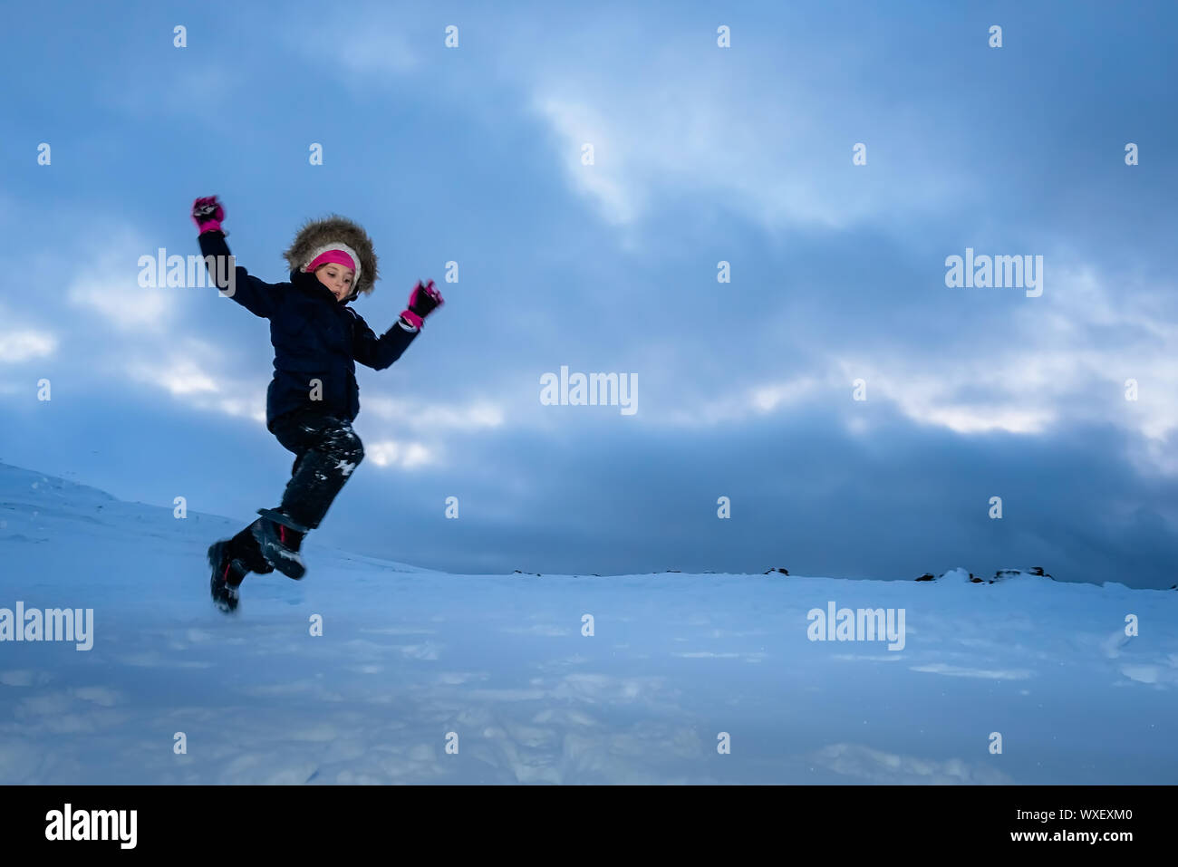 Happy little girl jumping in the snow Stock Photo - Alamy