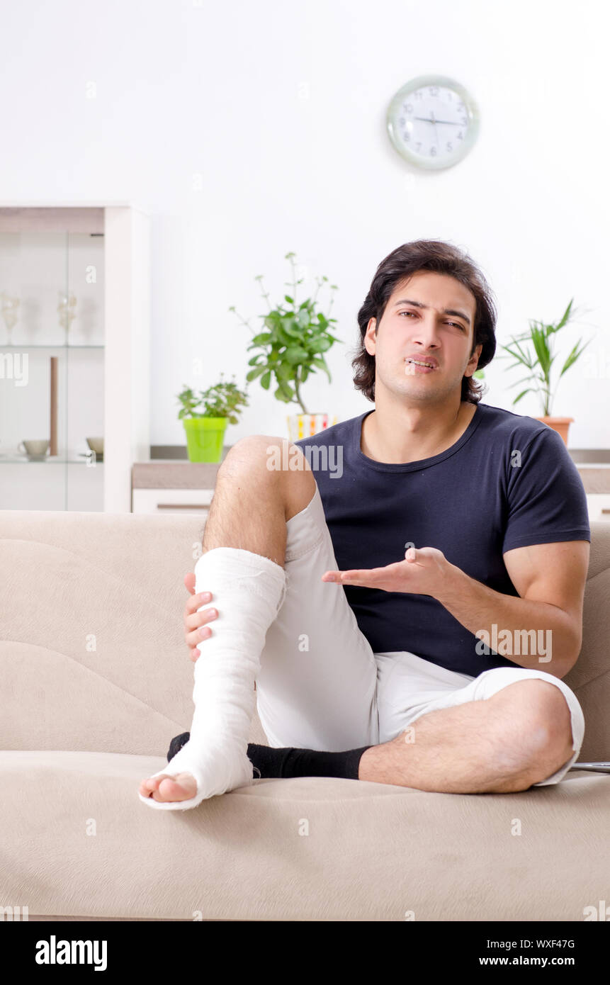 Leg injured young man suffering at home Stock Photo - Alamy