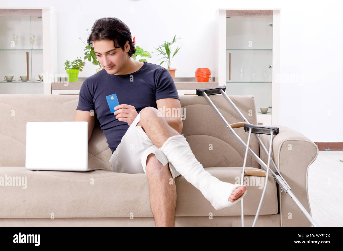 Leg injured young man suffering at home Stock Photo - Alamy