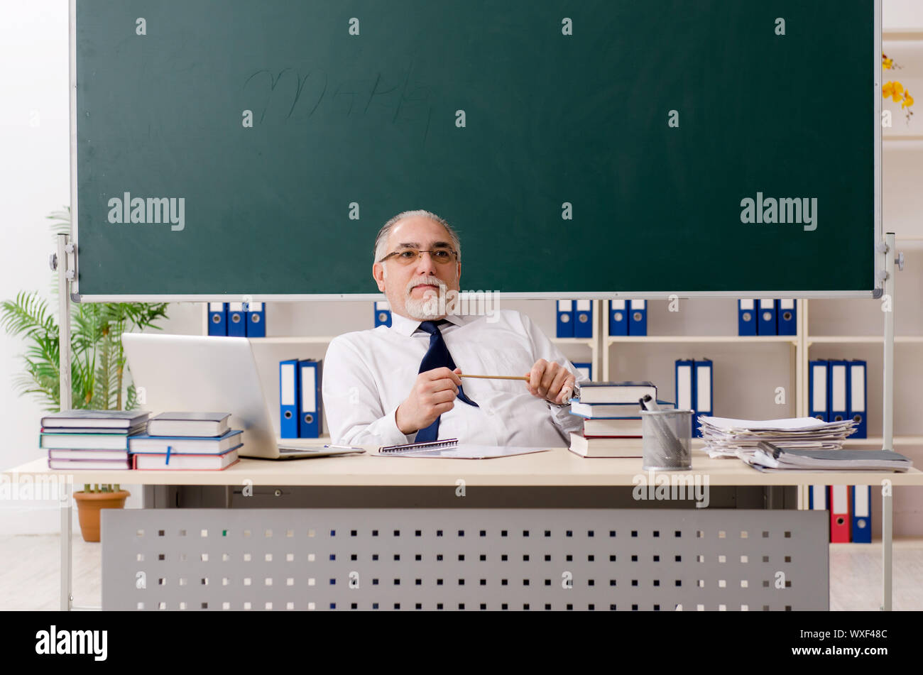 Aged male teacher in front of chalkboard Stock Photo - Alamy