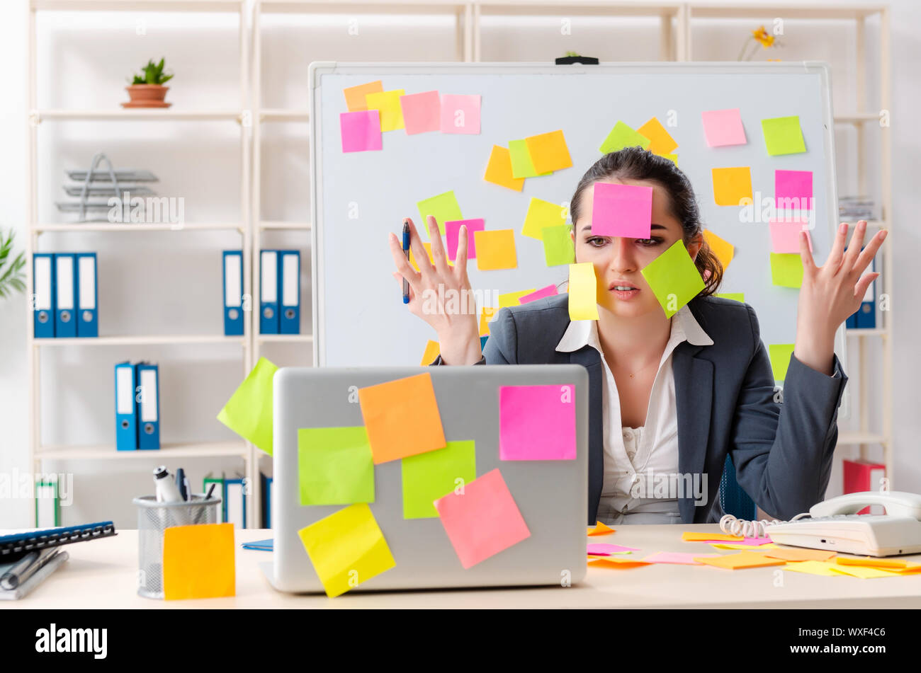 Young female employee in conflicting priorities concept Stock Photo - Alamy
