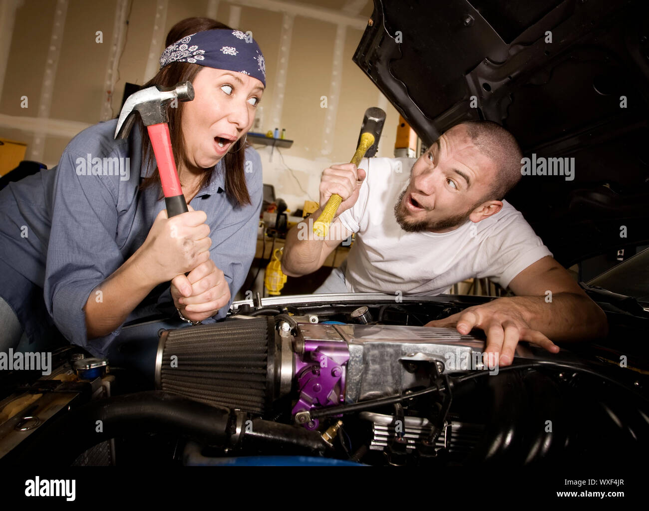 Hapless mechanics working on car engine with hammers Stock Photo - Alamy