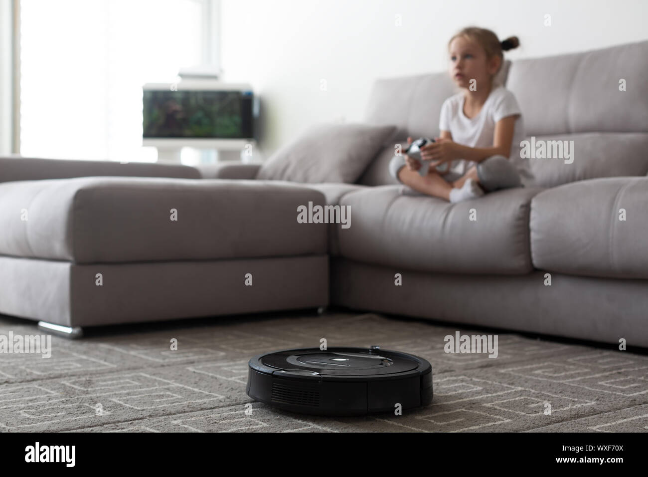 Robotic vacuum cleaning room while girl playing video game Stock Photo ...