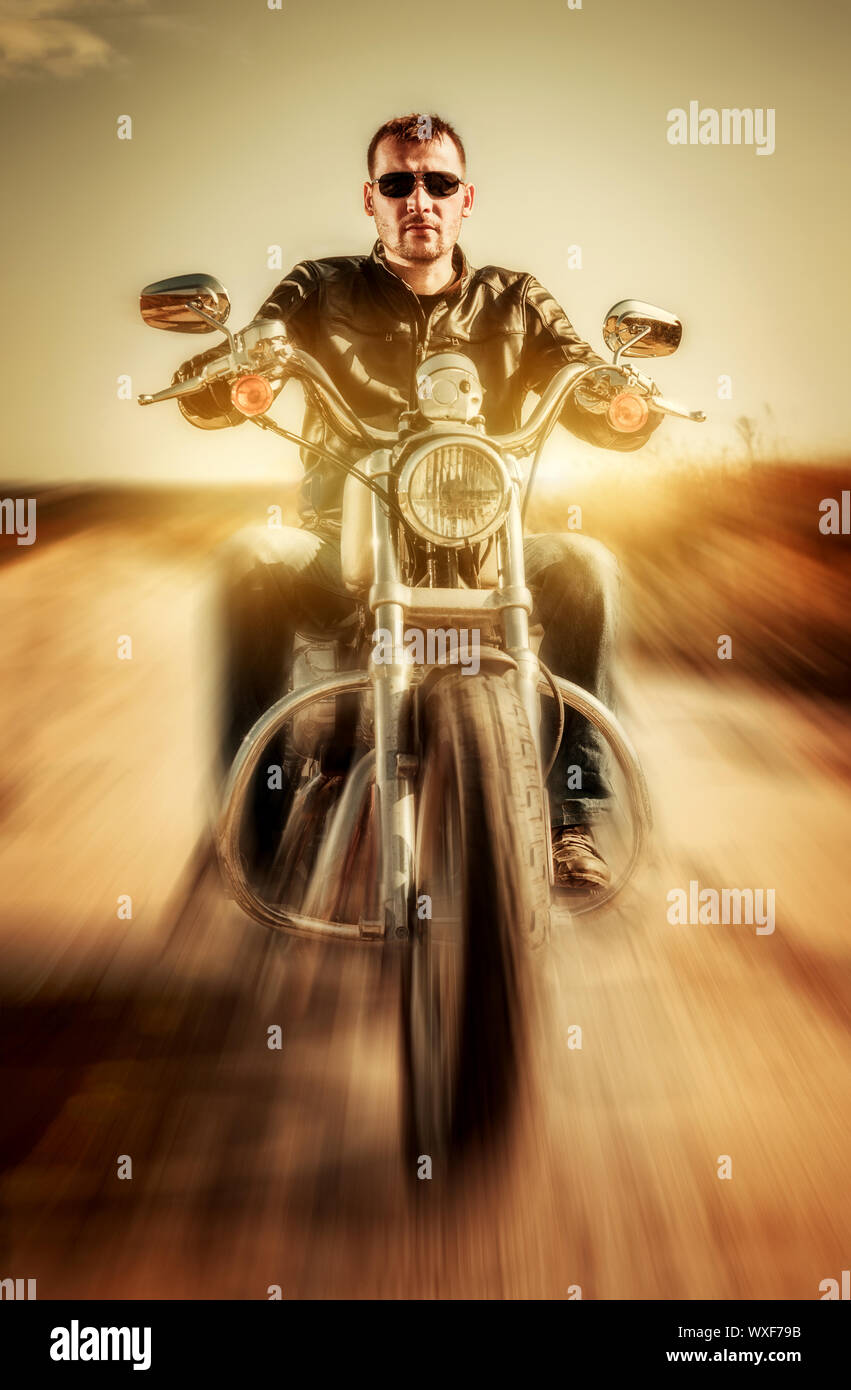Biker in a leather jacket riding a motorcycle on the road Stock Photo ...