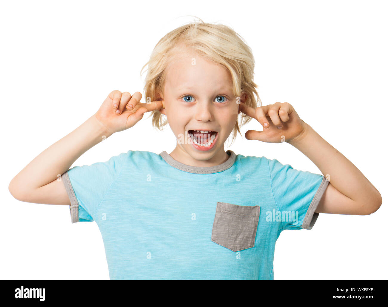 A cute cheeky young boy smiling and sticking his fingers in his ears ...