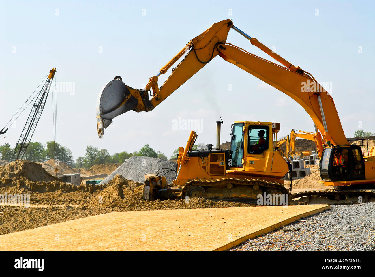 Yellow bulldozer machines digging and moving earth at construction site ...