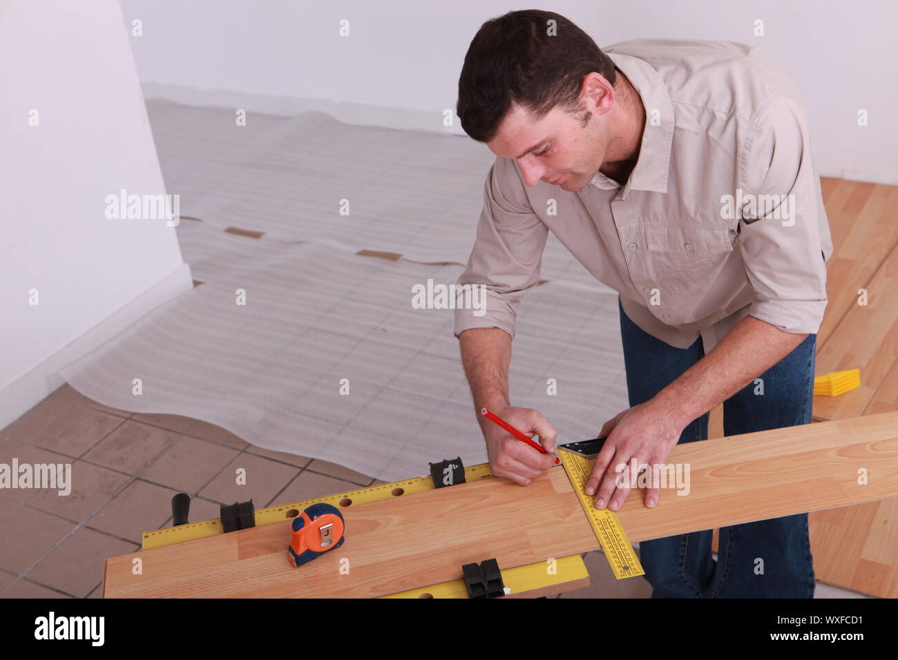 Man measuring plank of laminate flooring Stock Photo - Alamy