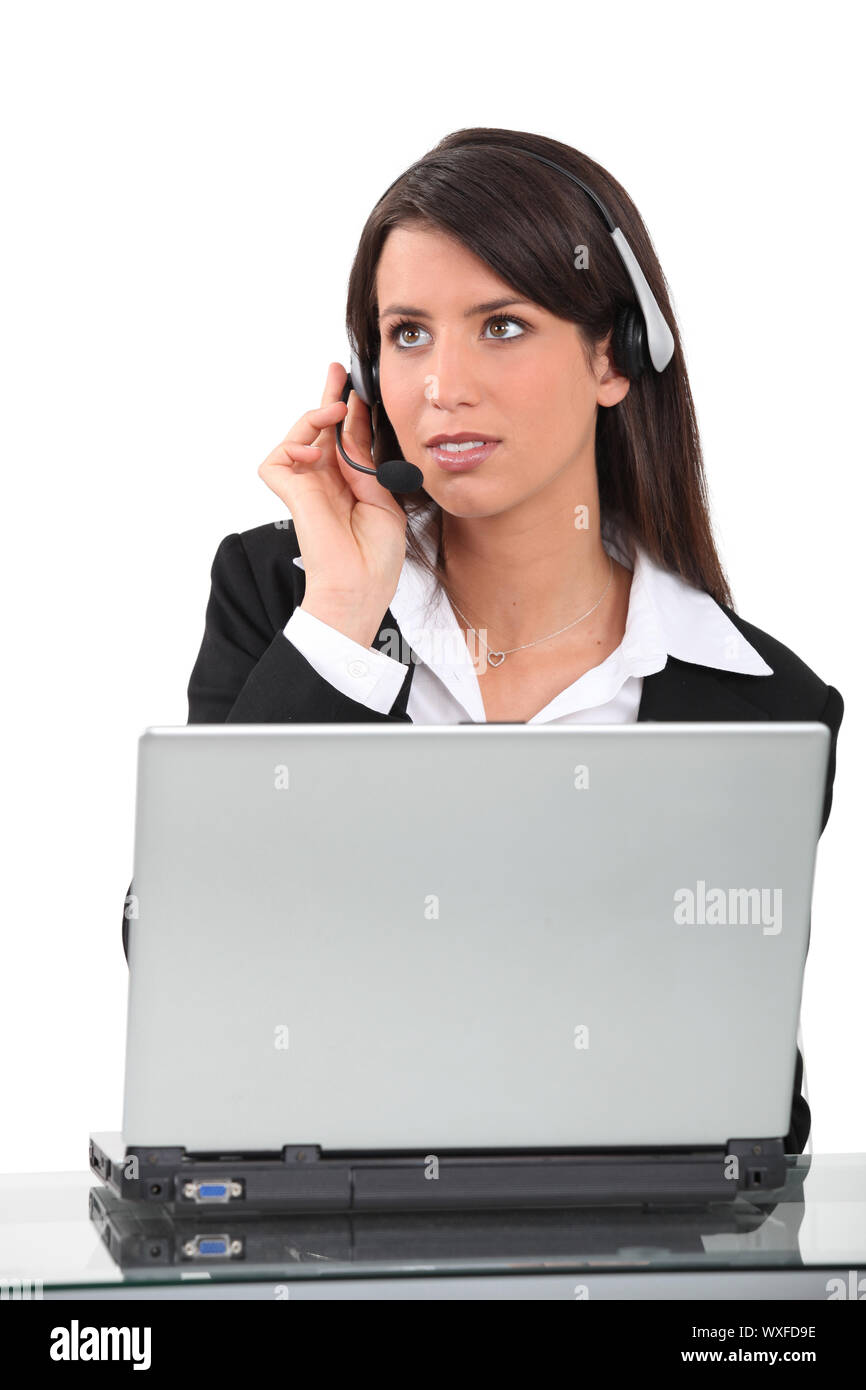 Woman wearing telephone head-set sat in front of laptop computer Stock ...