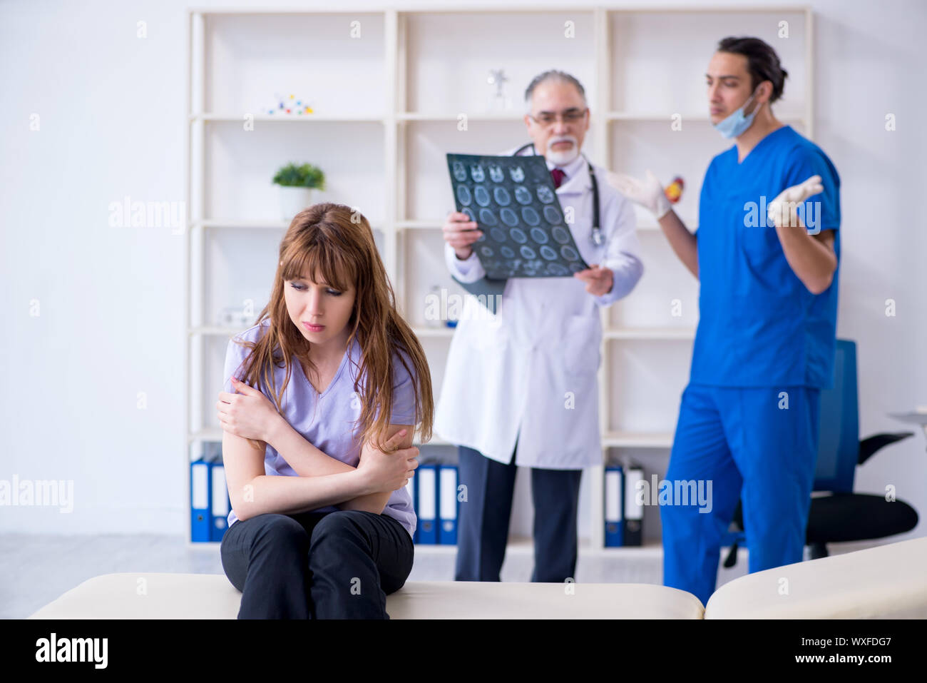 Two doctors examining young woman Stock Photo - Alamy