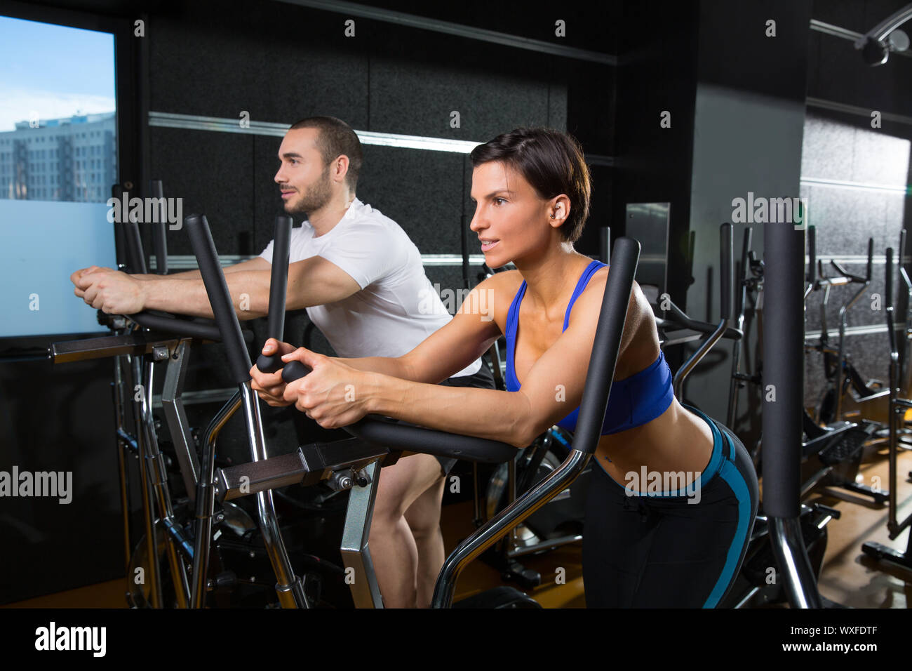 elliptical walker trainer man and woman at black gym training aerobics ...