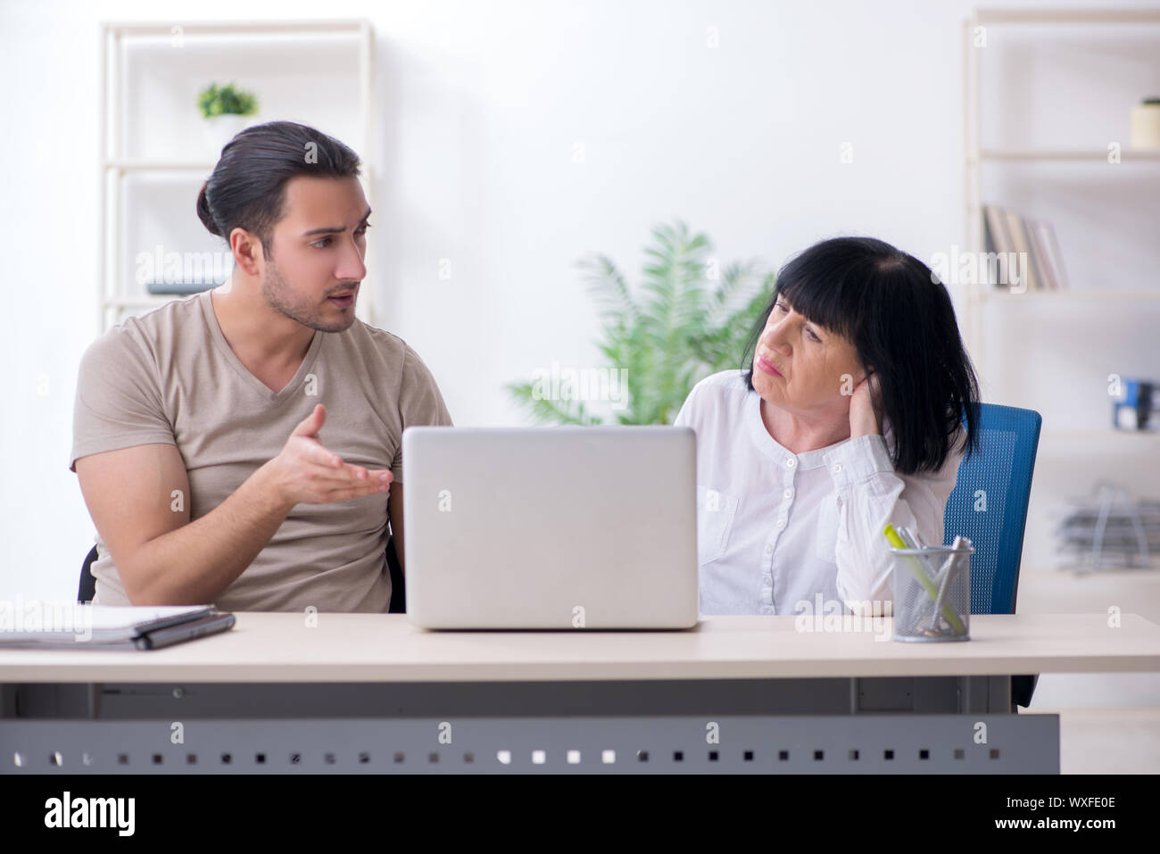 Young male employee explaining to old female colleague how to us Stock ...