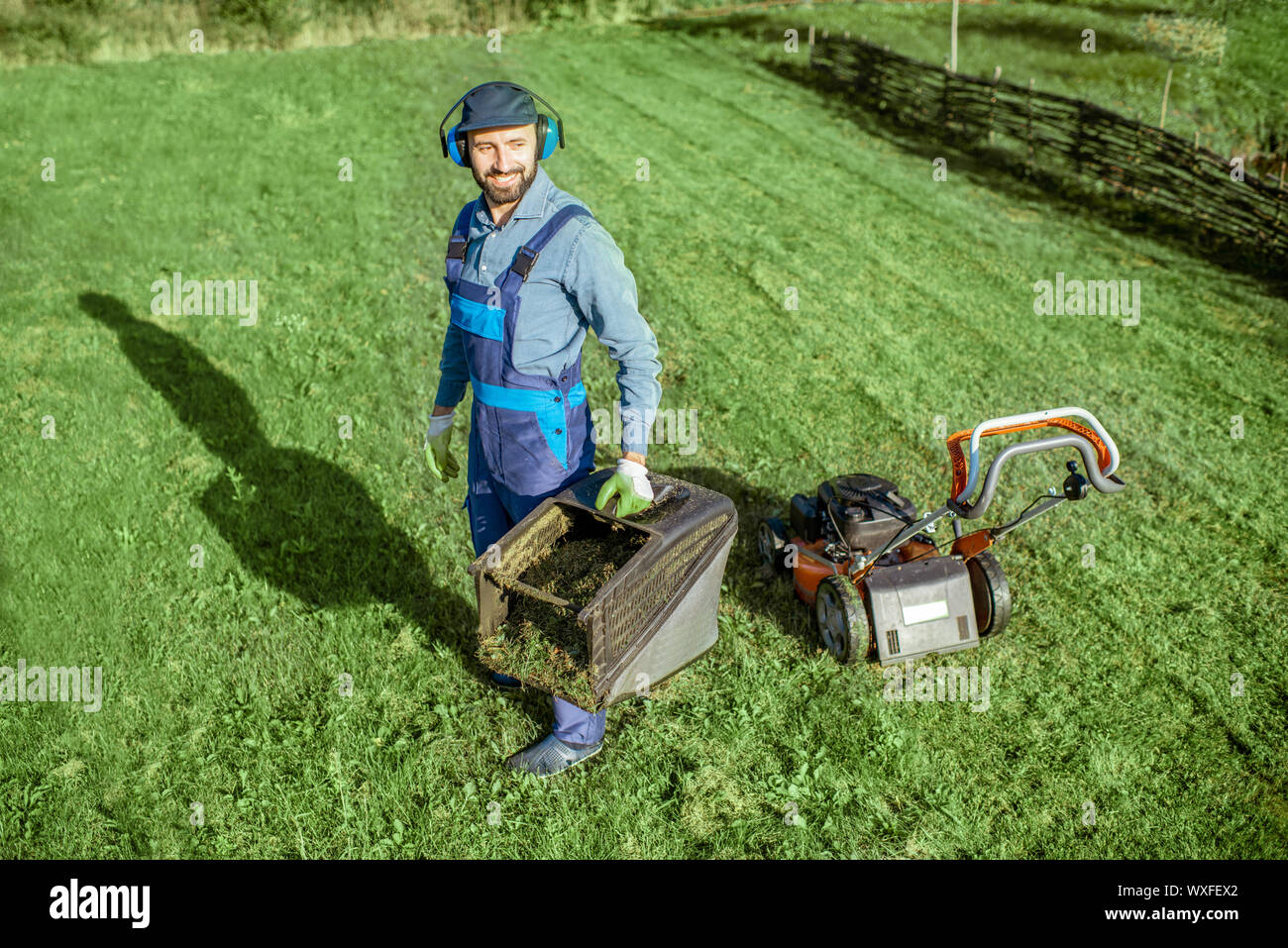 Professional gardener in protective workwear carrying basket full of ...