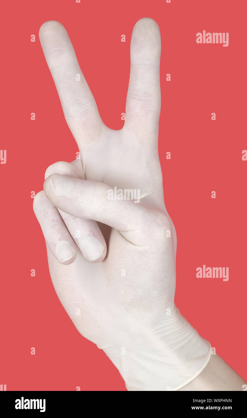 Hand in glove showing gesture victory on red Stock Photo - Alamy