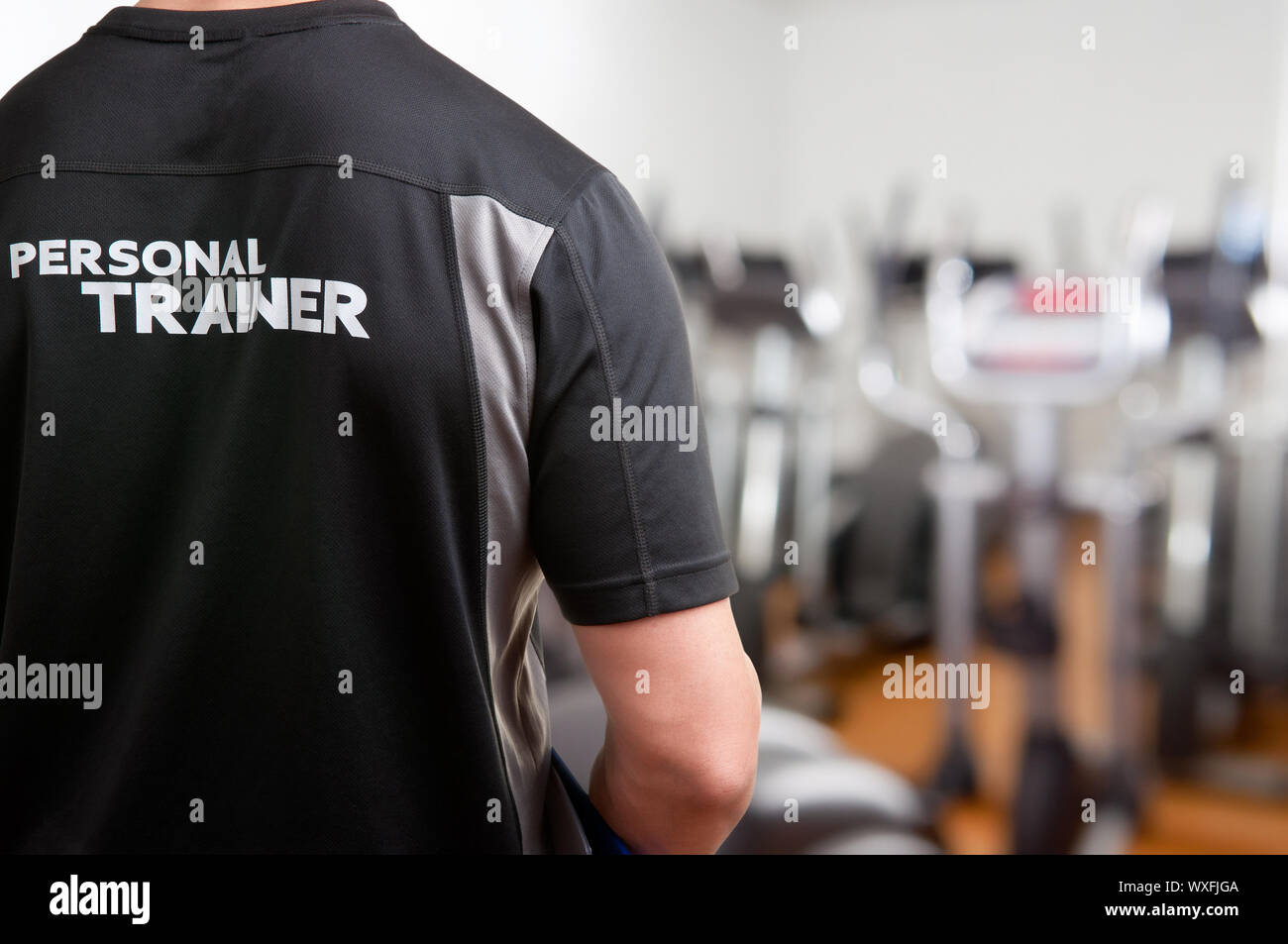 Personal Trainer, with his back facing the camera, looking at a gym ...